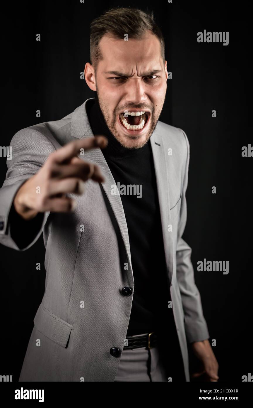 portrait of a young businessman in a gray suit, very angry yelling and ...
