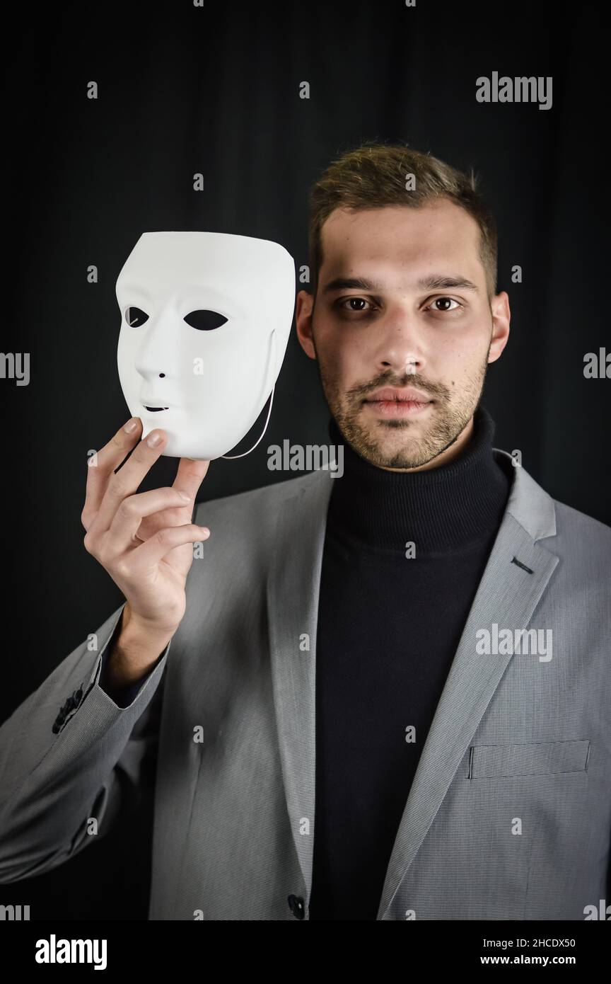 Be yourself - young man holding a white mask next to his face - concept ...