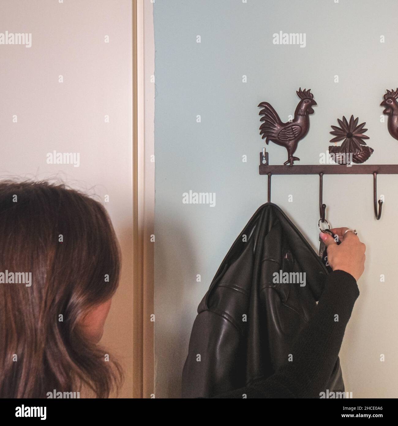 Brunette young woman hanging her keys from the metal hanger attached to ...