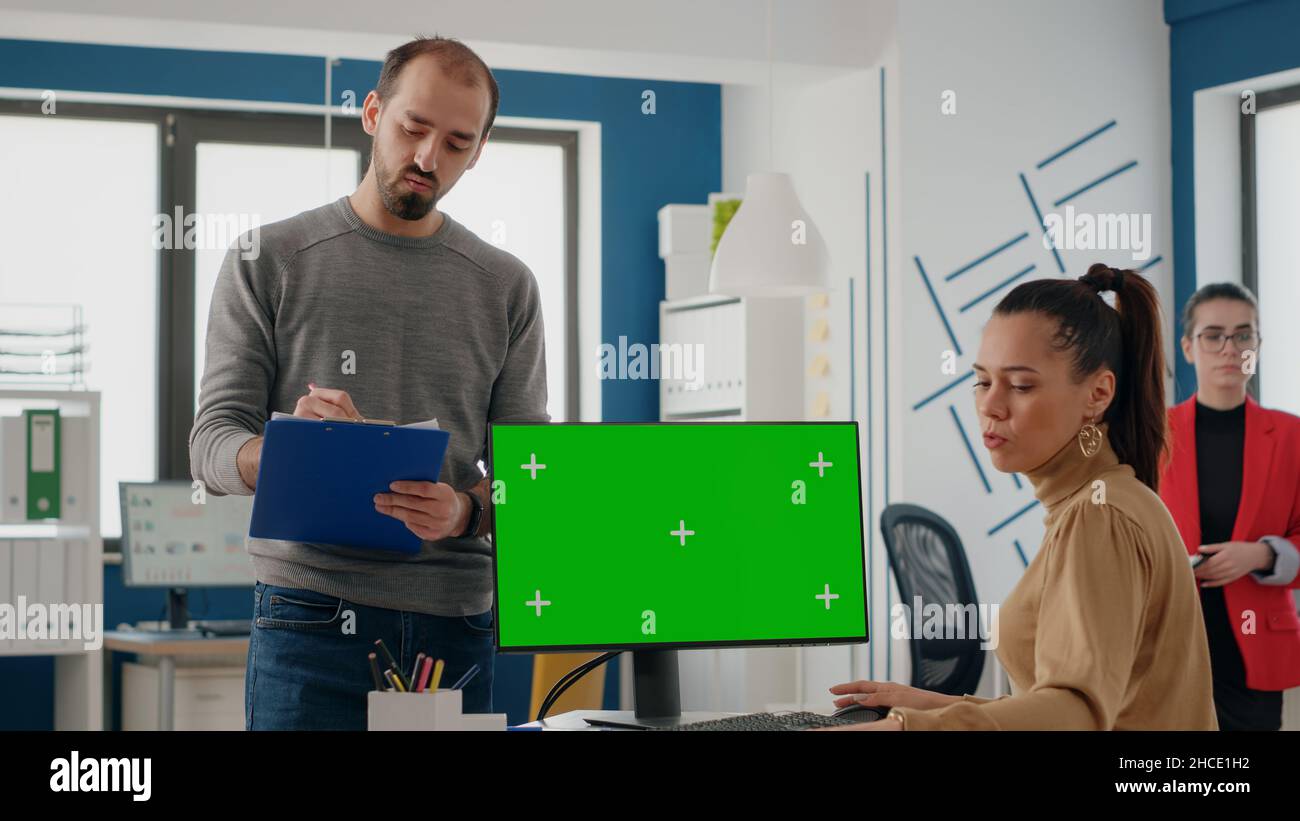 Workmates using computer with green screen on display in business ...