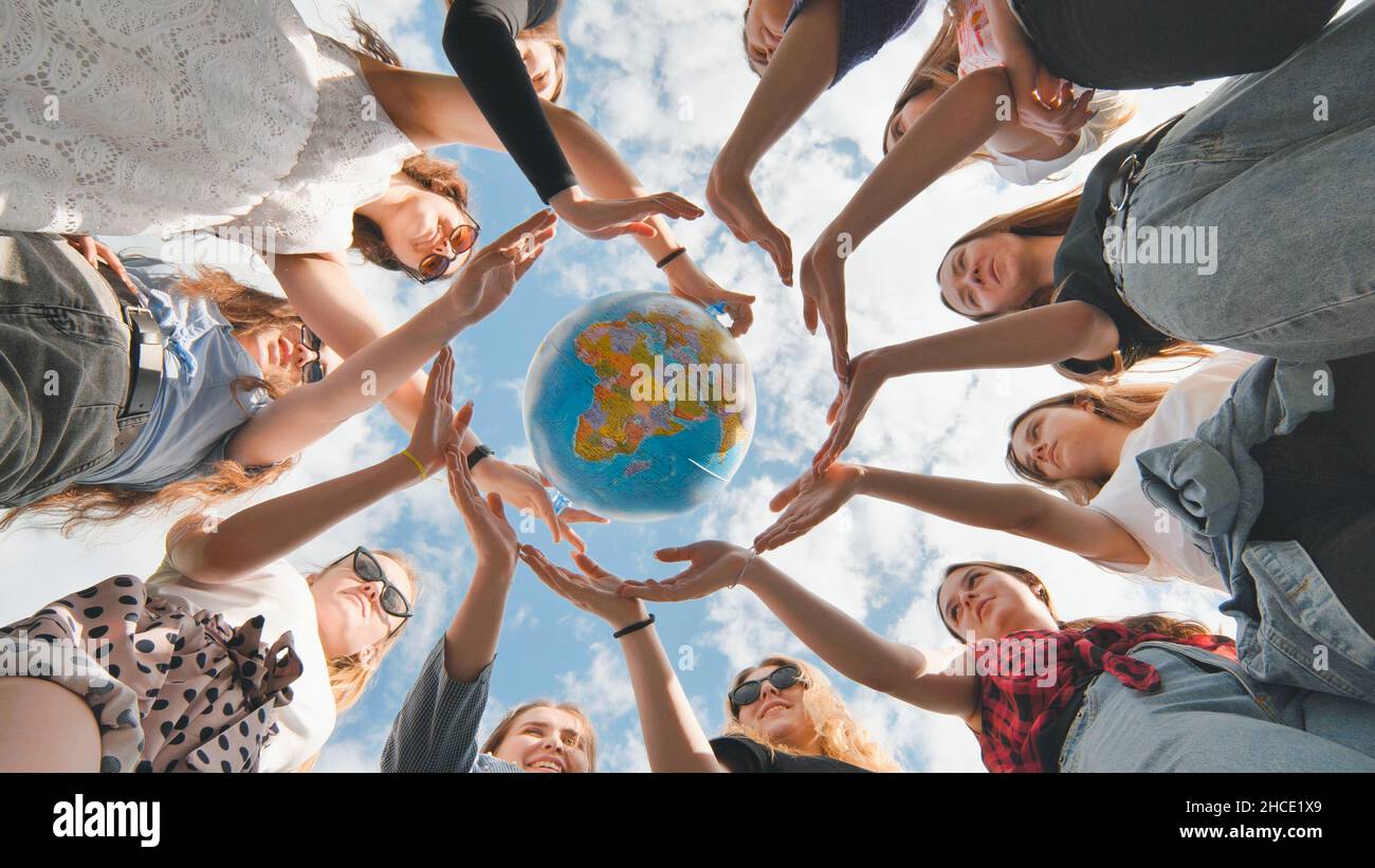 Earth conservation concept. 11 girls surround the rotating earth globe ...