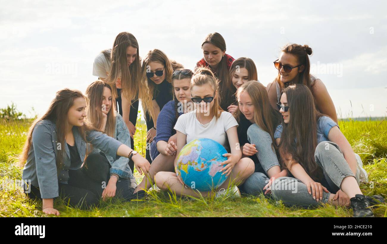 A group of cheerful girls is exploring the globe of the world in the ...
