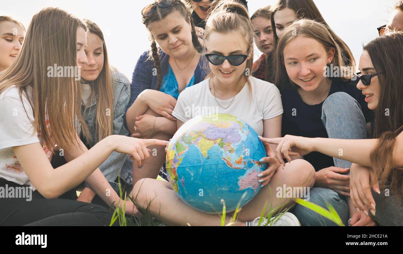 A group of cheerful girls is exploring the globe of the world in the ...
