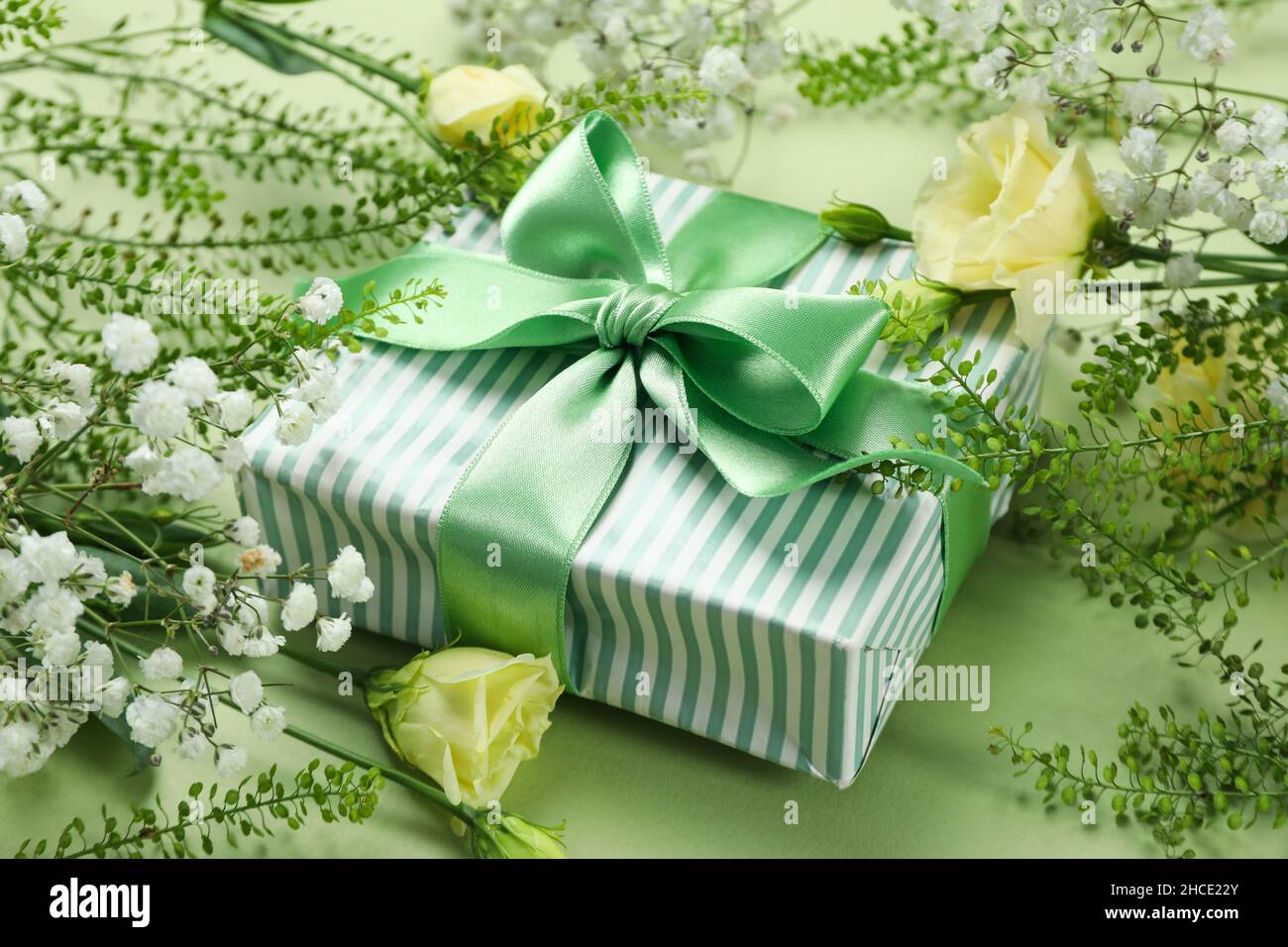 Gift box with flowers on green background Stock Photo - Alamy