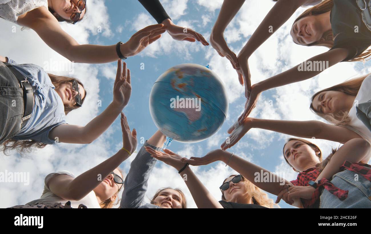 Earth conservation concept. 11 girls surround the rotating earth globe ...