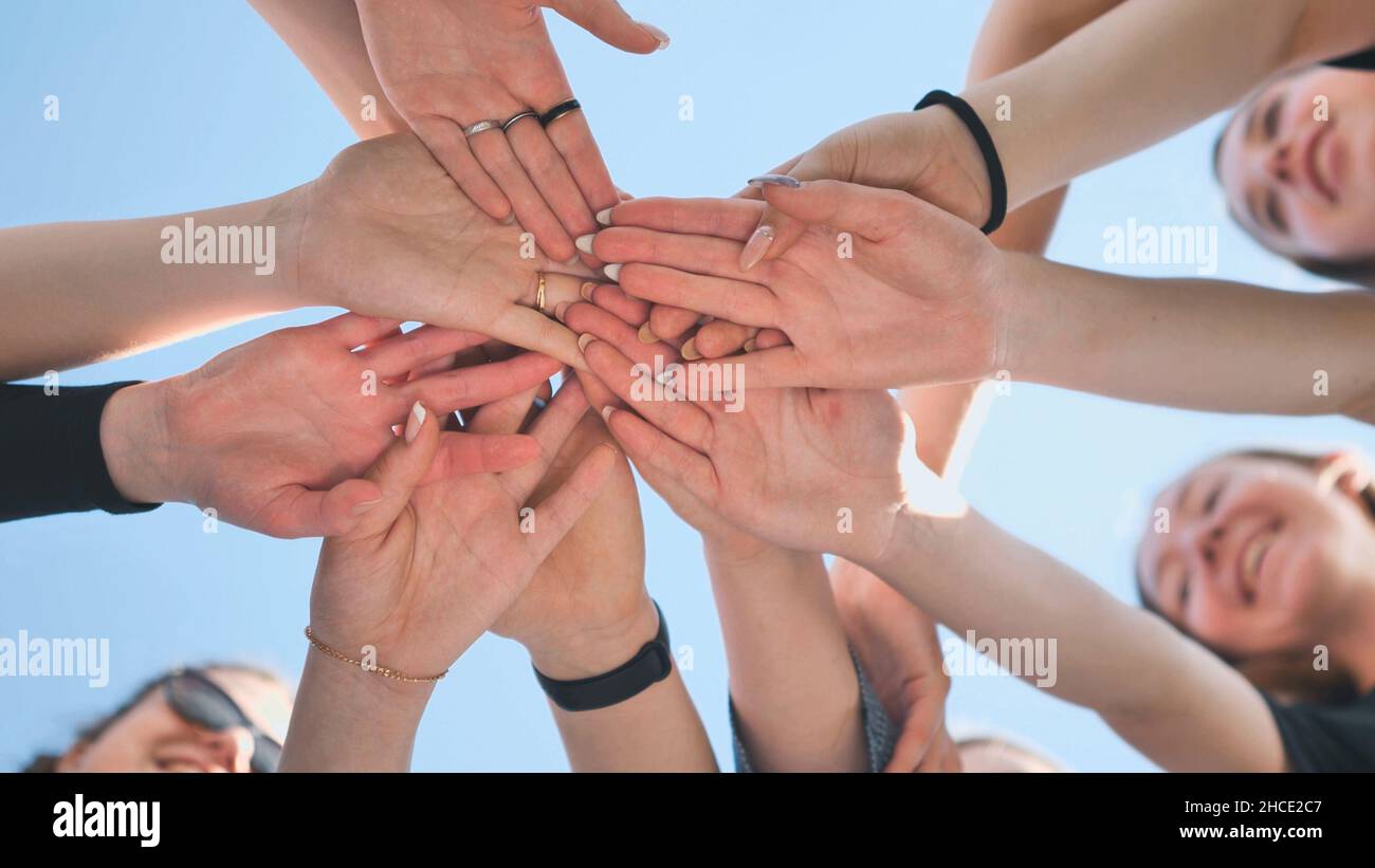 Cheerful girls join hands together as a sign of unity and joint ...