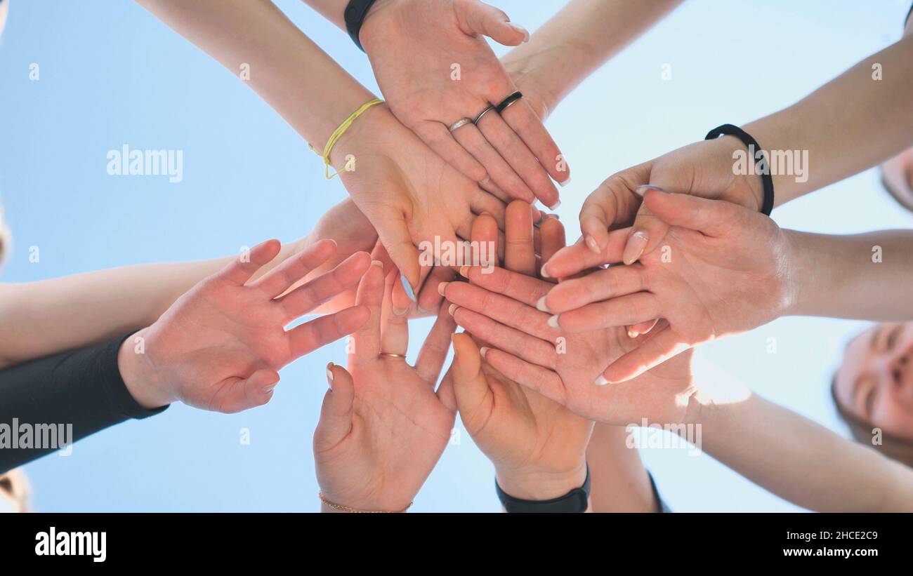 Cheerful girls join hands together as a sign of unity and joint ...
