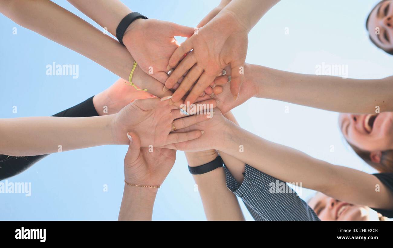 Cheerful girls join hands together as a sign of unity and joint ...