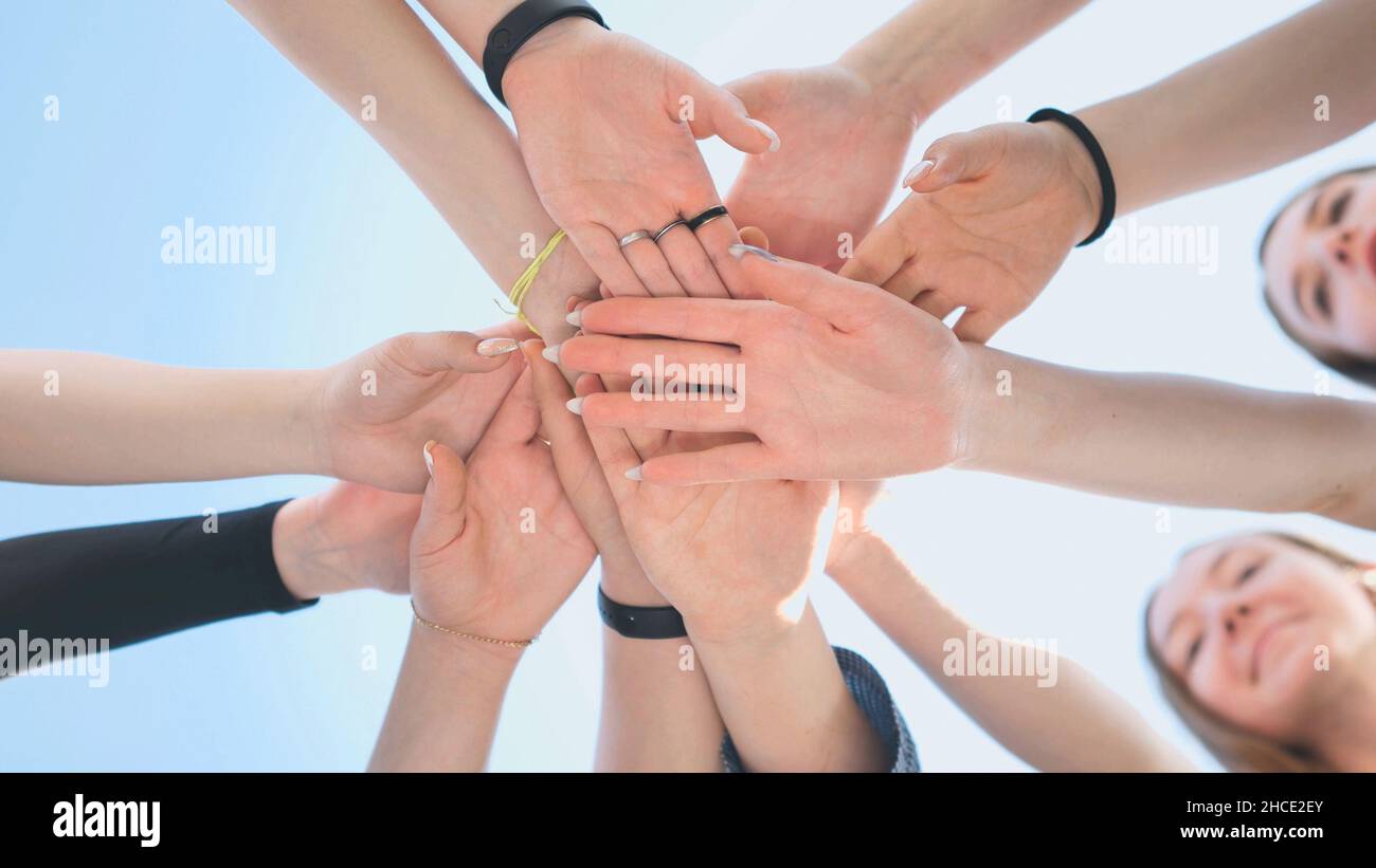 Cheerful girls join hands together as a sign of unity and joint ...