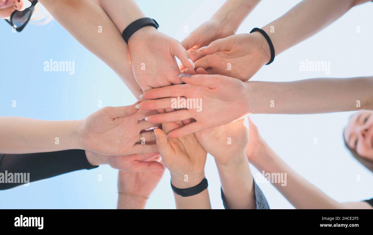 Cheerful girls join hands together as a sign of unity and joint ...