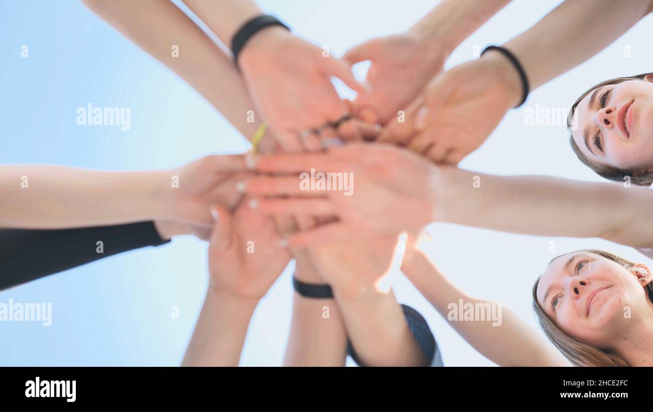 Cheerful girls join hands together as a sign of unity and joint ...