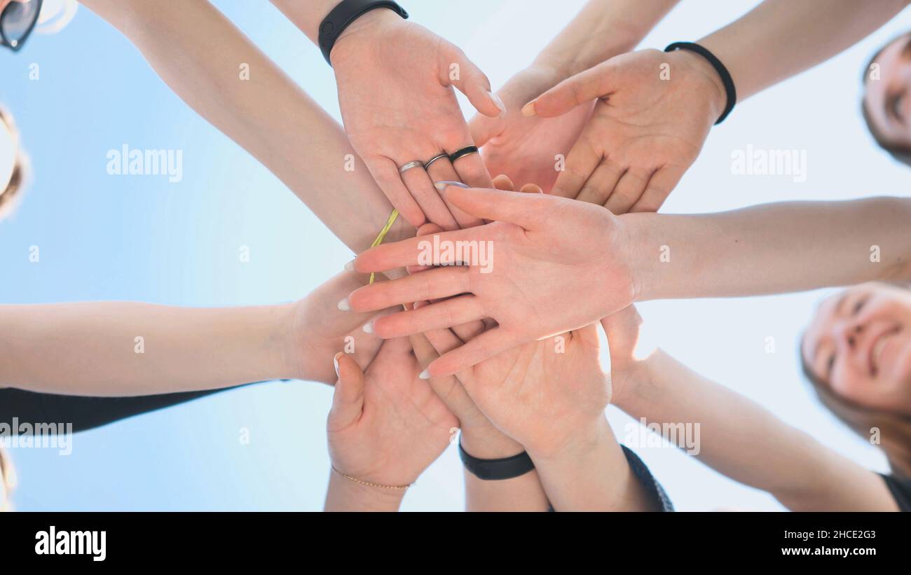 Cheerful girls join hands together as a sign of unity and joint ...