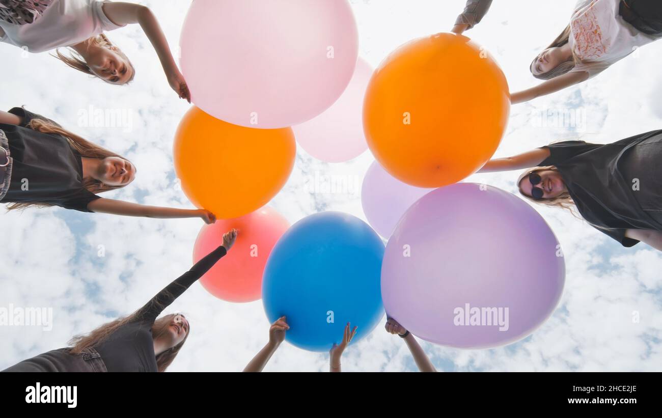 Cheerful girlfriends connect large colorful balls in a circle Stock ...