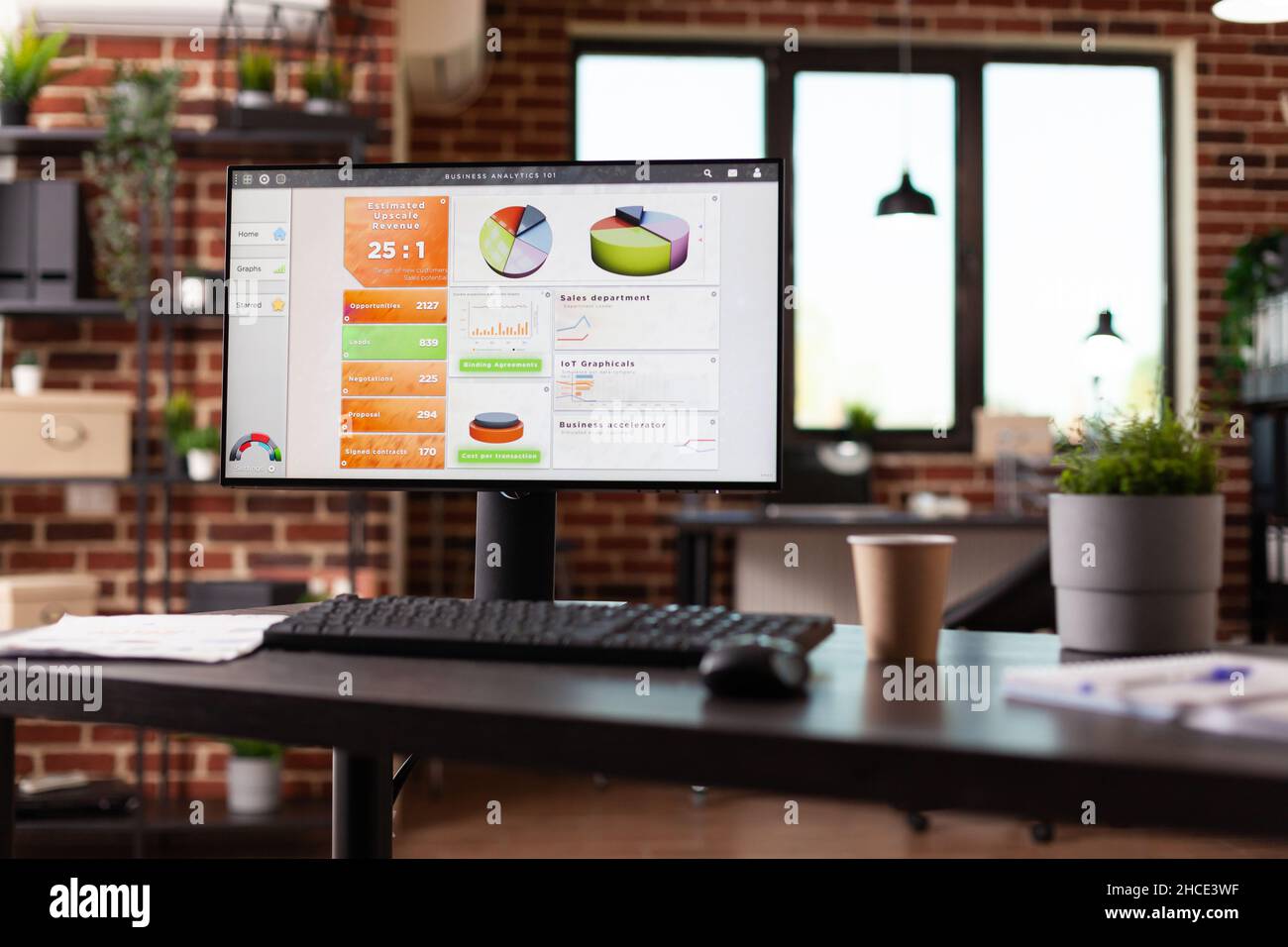Computer with business charts on desk in empty workplace. Monitor with ...