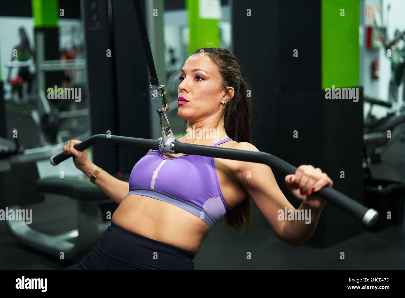 Positive fit ethnic female in activewear doing shoulder exercises on ...