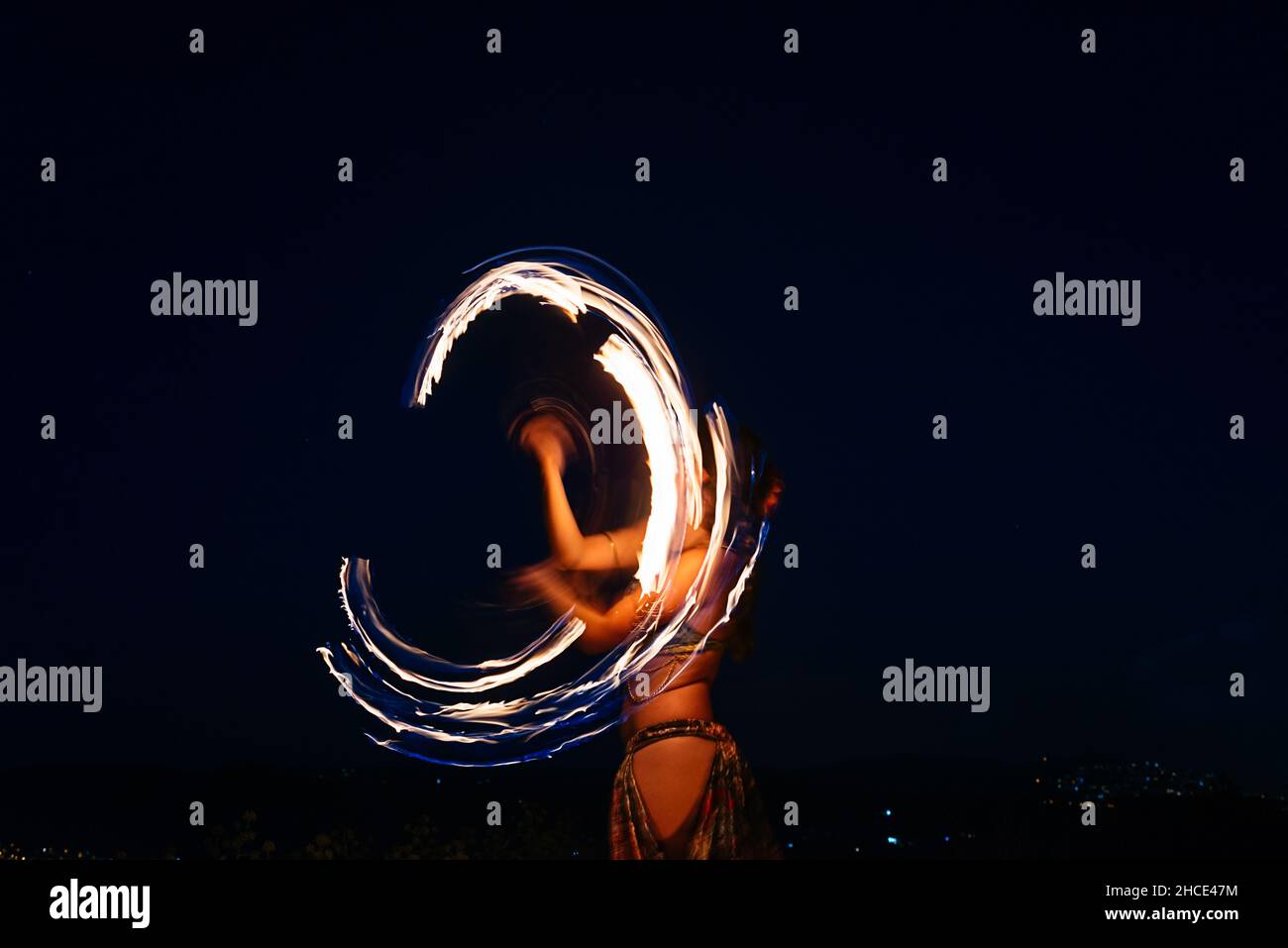 Long exposure of unrecognizable skilled fire dancer with fire fan ...