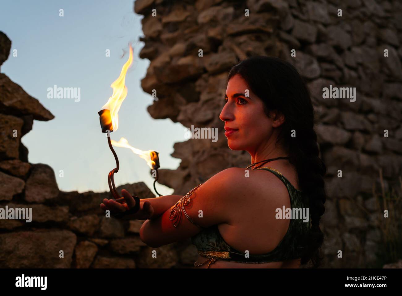 Side view of talented female fire dancer in costume standing with ...