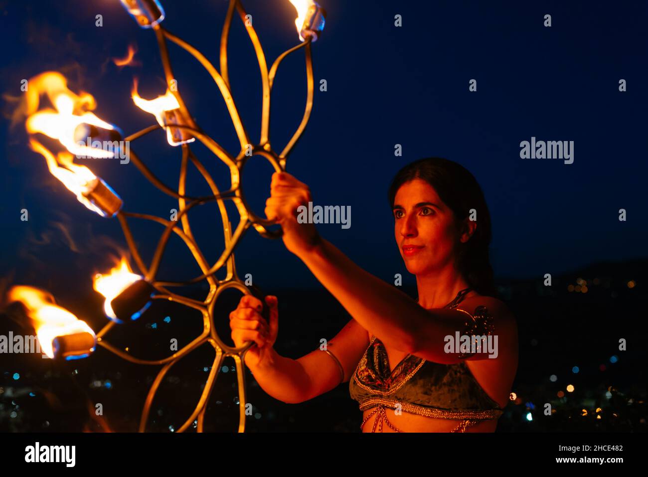 Talented female fire dancer in costume standing with burning fire fans ...