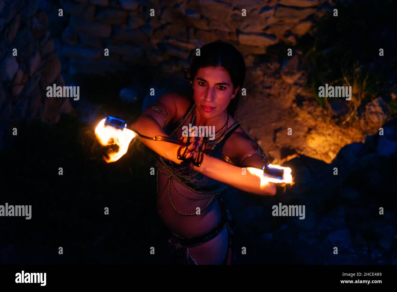 From above talented female fire dancer in costume standing with burning ...