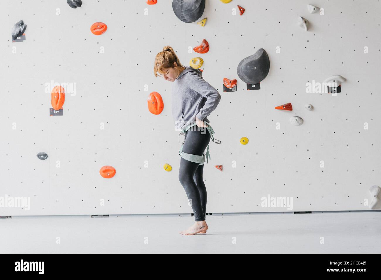 Full body side view of sportive barefoot female climber putting on ...