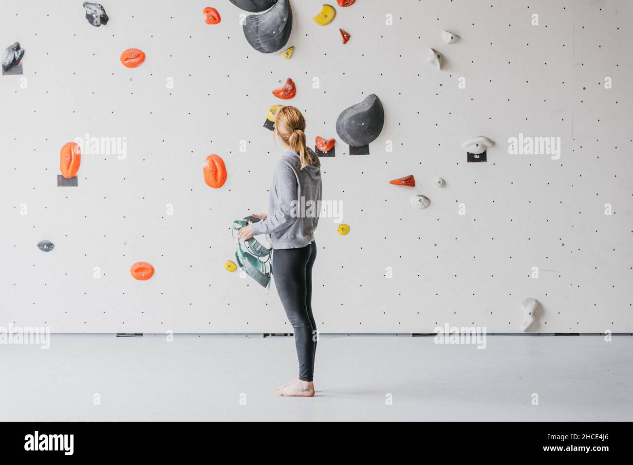 Full body side view of sportive barefoot female climber putting on ...