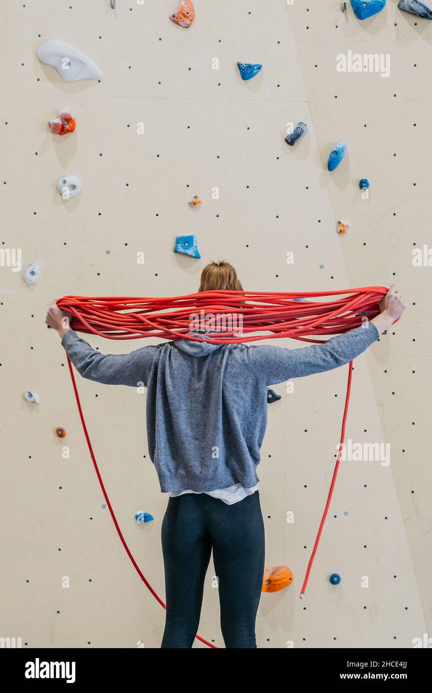 Back view of sportive female with ropes for climbing behind back ...