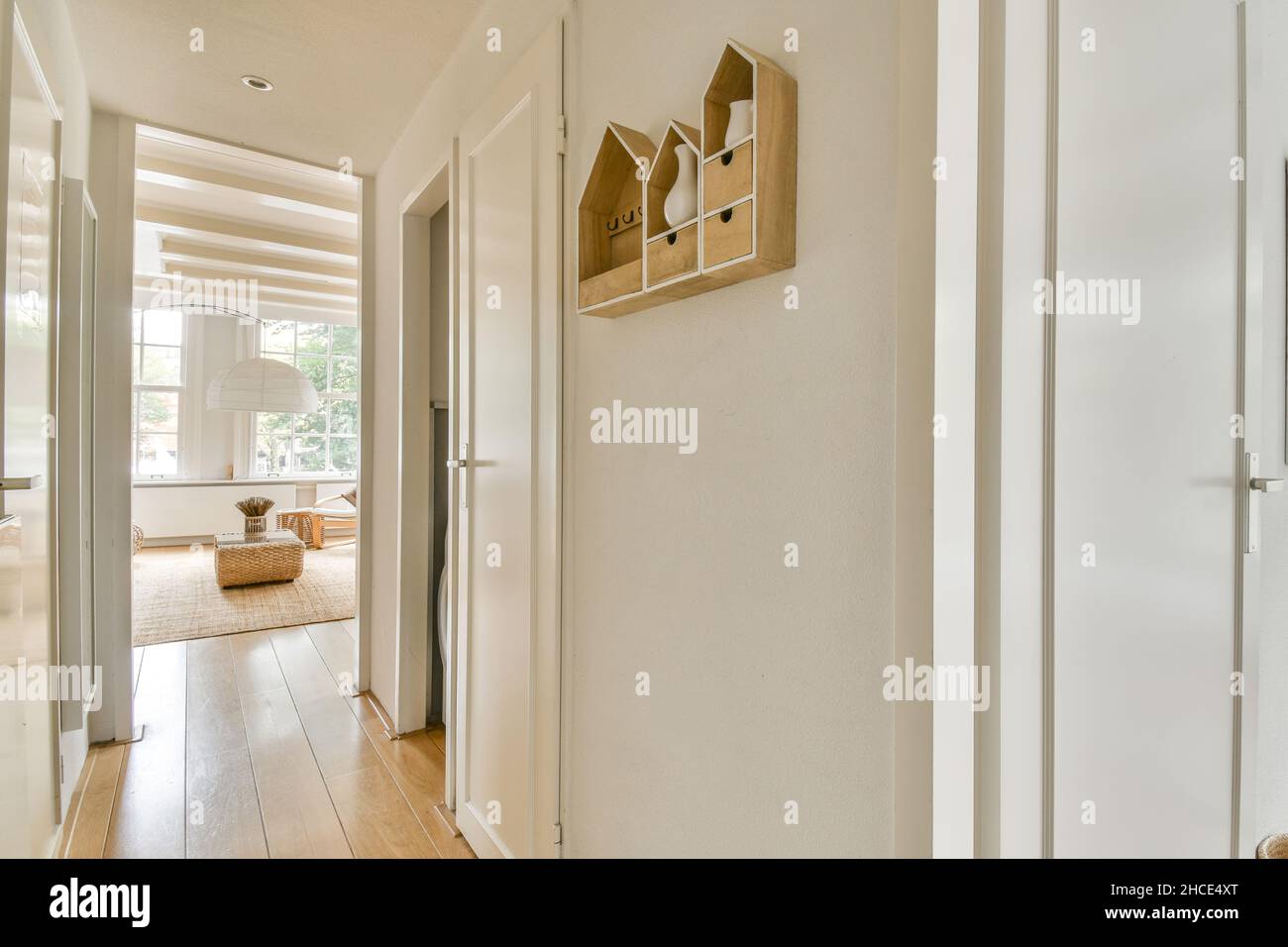 Corridor with wooden decoration on white wall and opened door of living ...