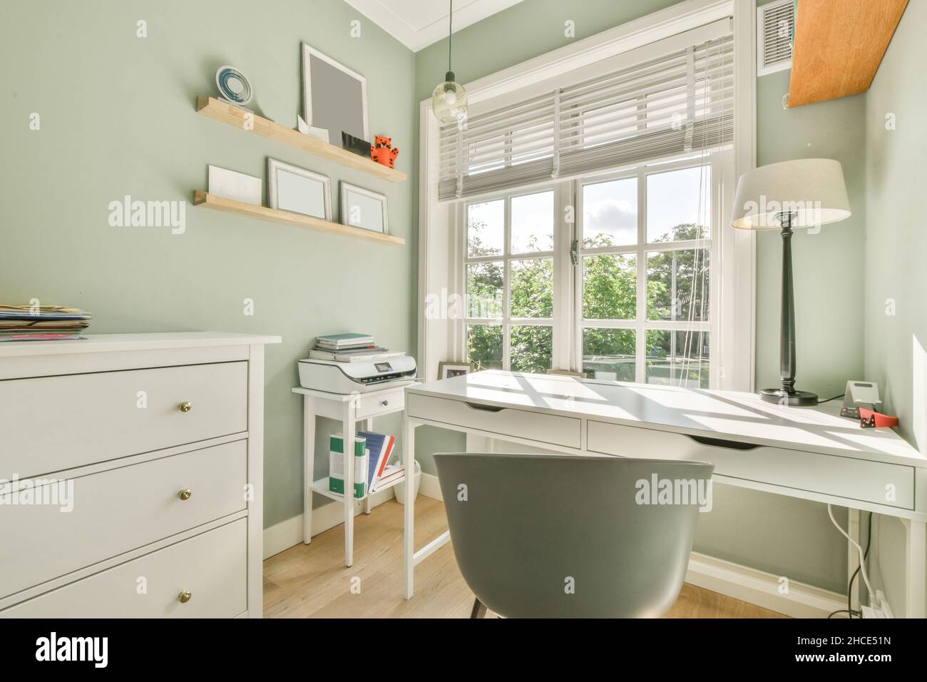 Chair at table with lamp placed near window in sunny study room with ...