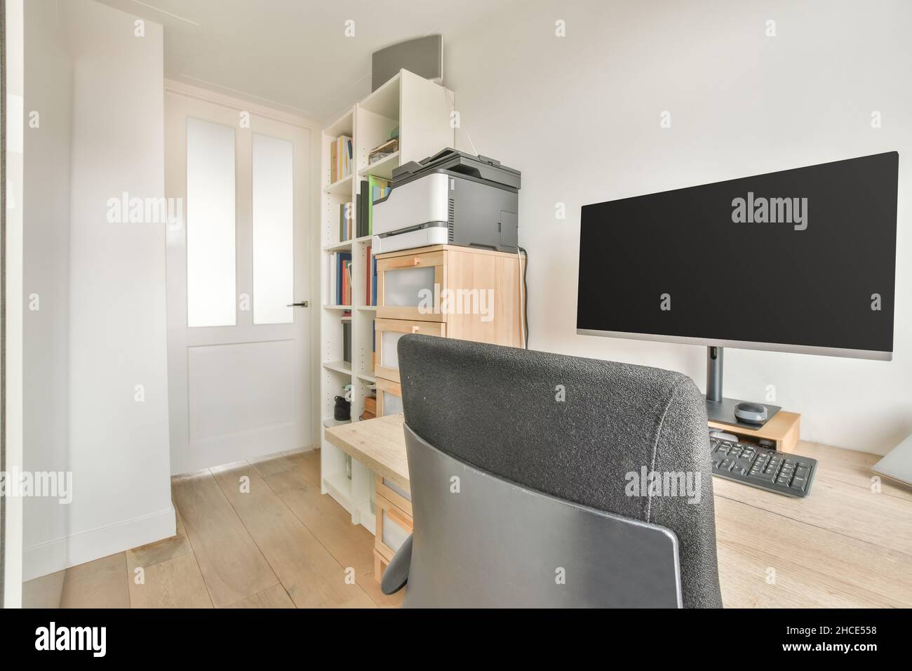 Comfortable chair placed at wooden desk with modern computer near ...