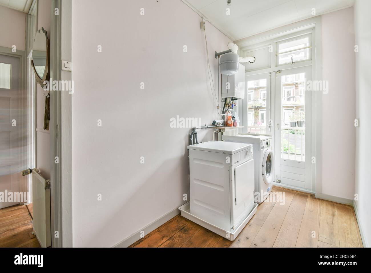 White washing machine placed on wooden floor in corner near wall ...