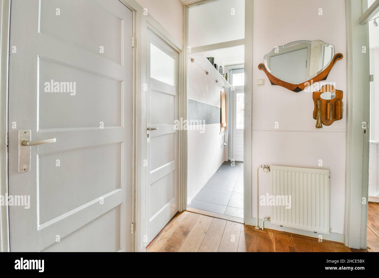 Exterior of light hallway with white walls and row of doors against ...