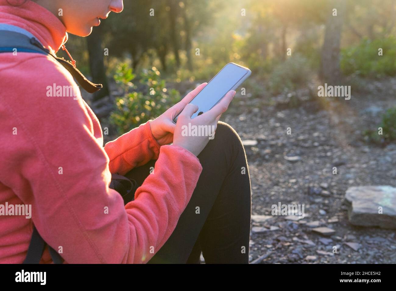 Side view of crop unrecognizable female hiker text messaging on modern ...