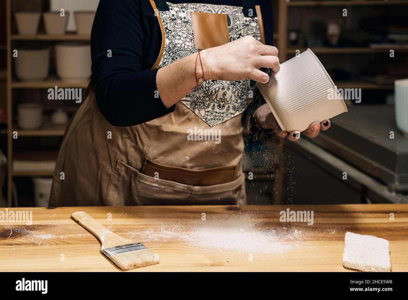 Crop unrecognizable female craftsWoman wearing apron making clay pot ...