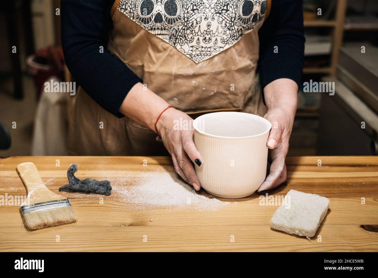 Crop unrecognizable female craftsWoman wearing apron making clay pot ...