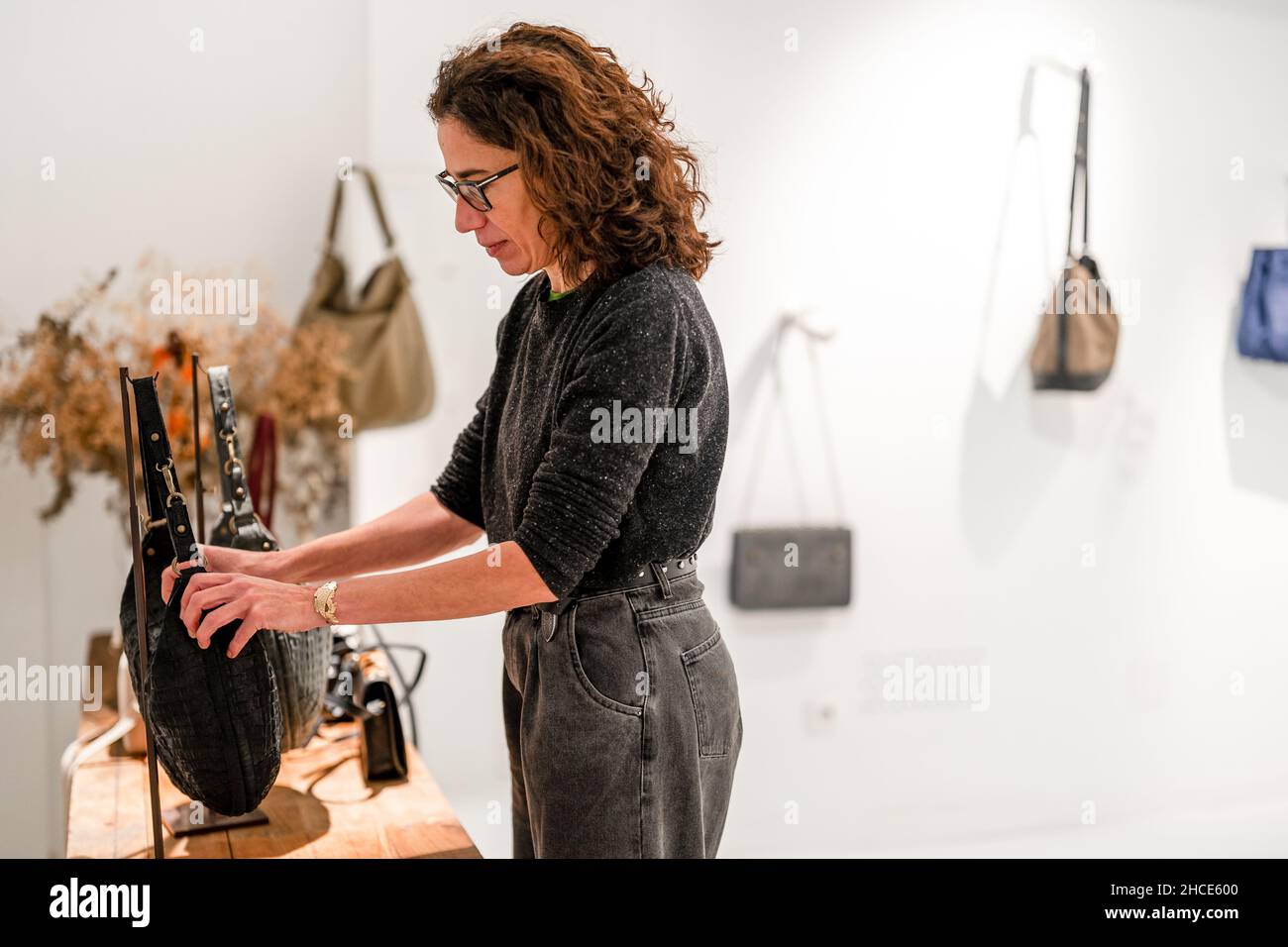 Side view of serious female designer standing near table with ...