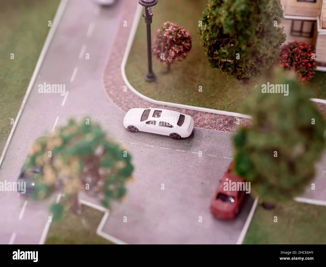 Model of street with miniature cars on the road with lawns and trees ...