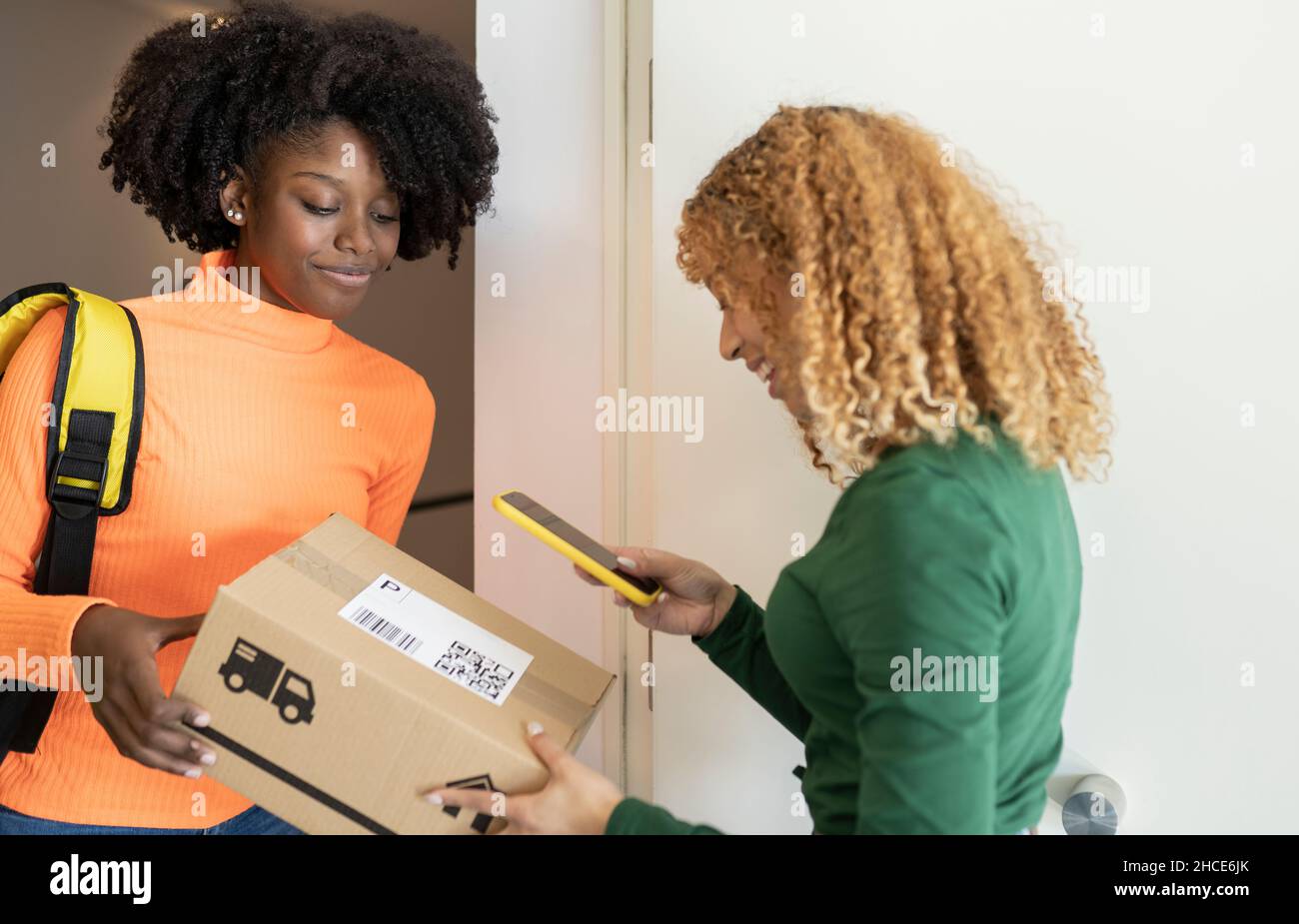 Young black female courier with backpack delivering parcel of internet ...