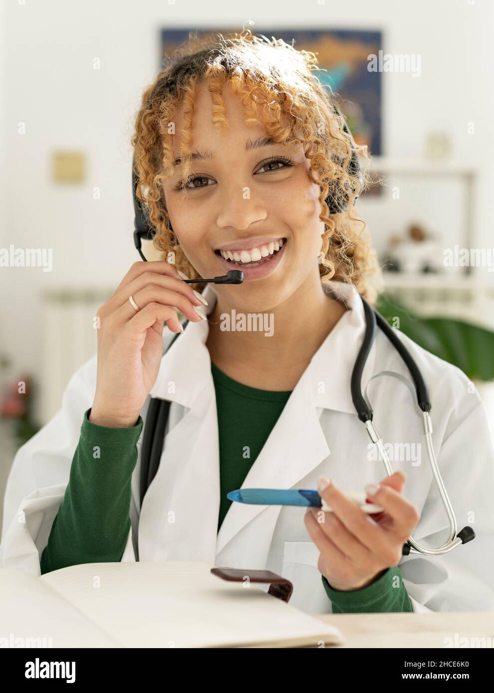 Smiling ethnic female doctor in headset with mic and stethoscope on ...