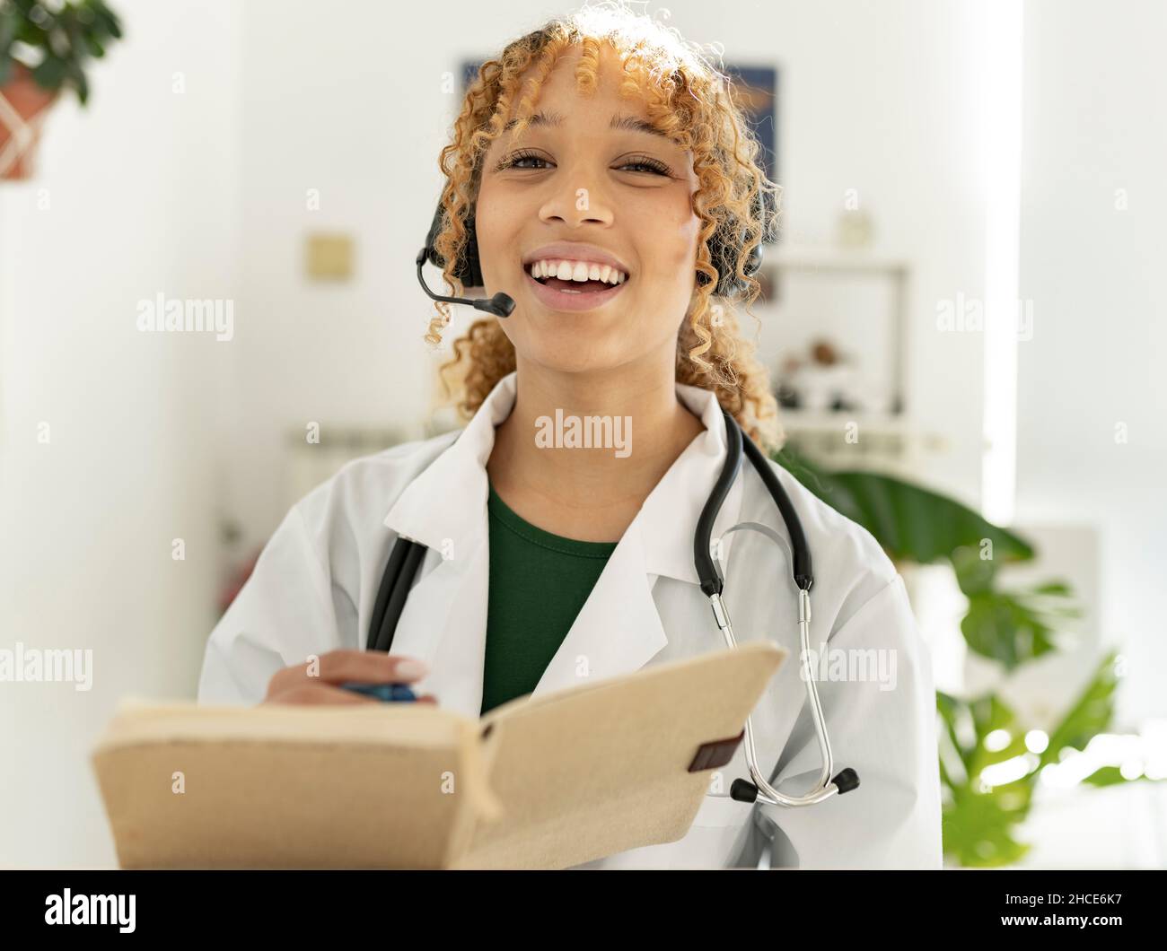 Smiling ethnic female doctor in headset with mic and stethoscope on ...