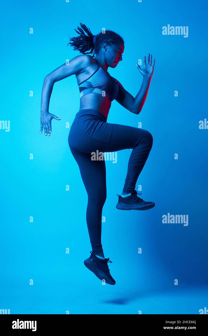 Full body side view of black Woman in activewear jumping in studio ...