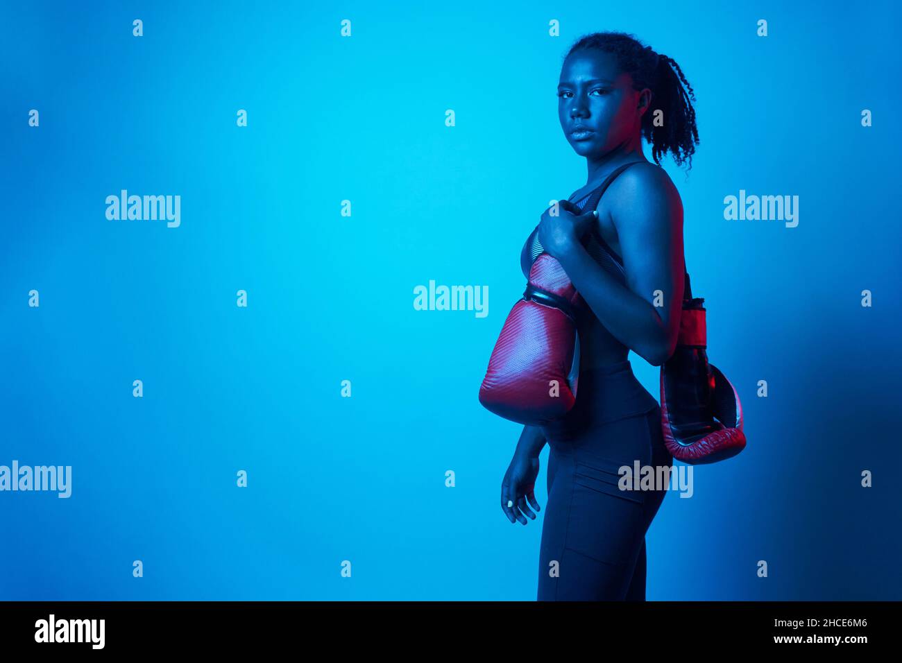 Side view of ethnic lady in sportswear standing with boxing gloves on ...