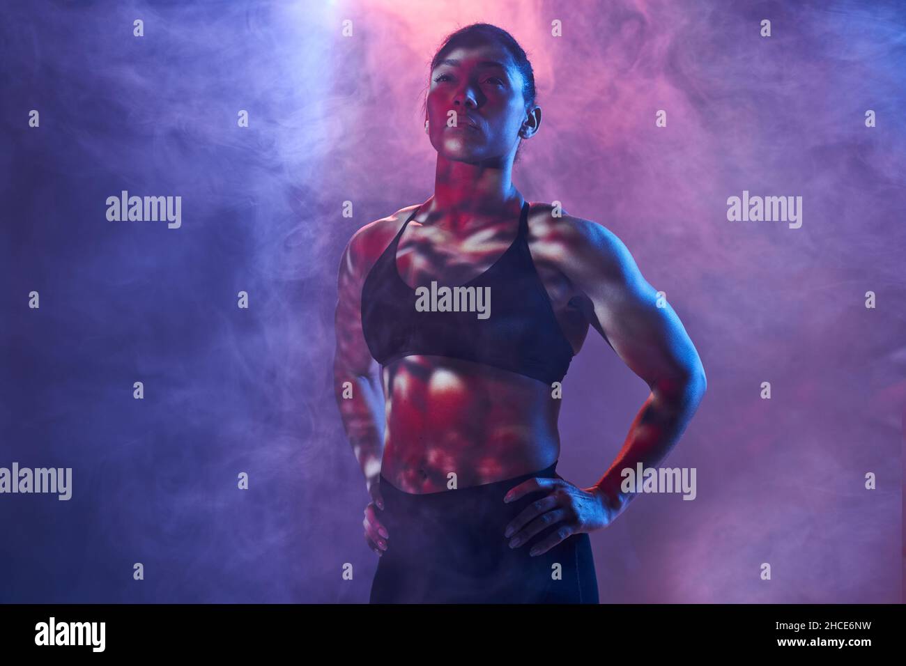 Confident slim female athlete in sportswear standing with hands on hips ...
