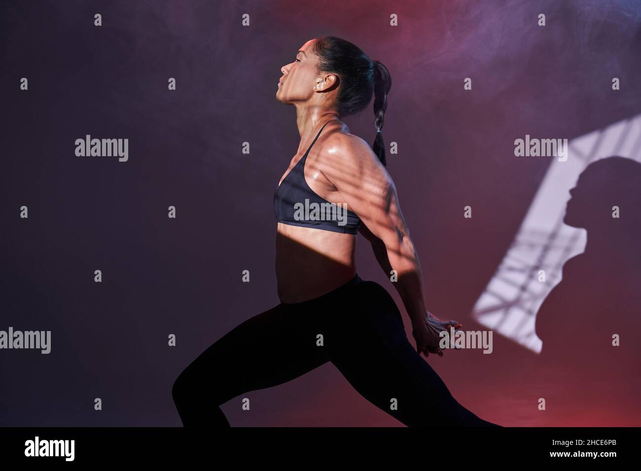 Side view of muscular young female in sportswear stretching body during ...