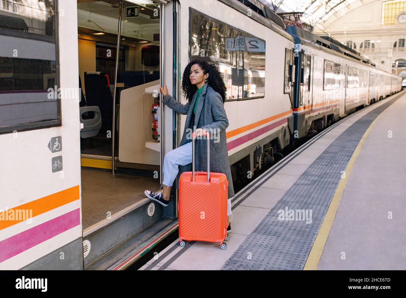 Side view of stylish African American female traveler in stylish coat ...