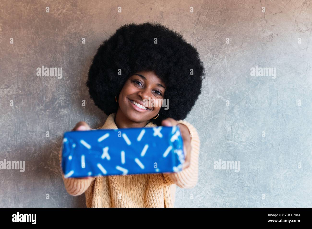 Cheerful young African American female with Afro hairstyle presenting ...