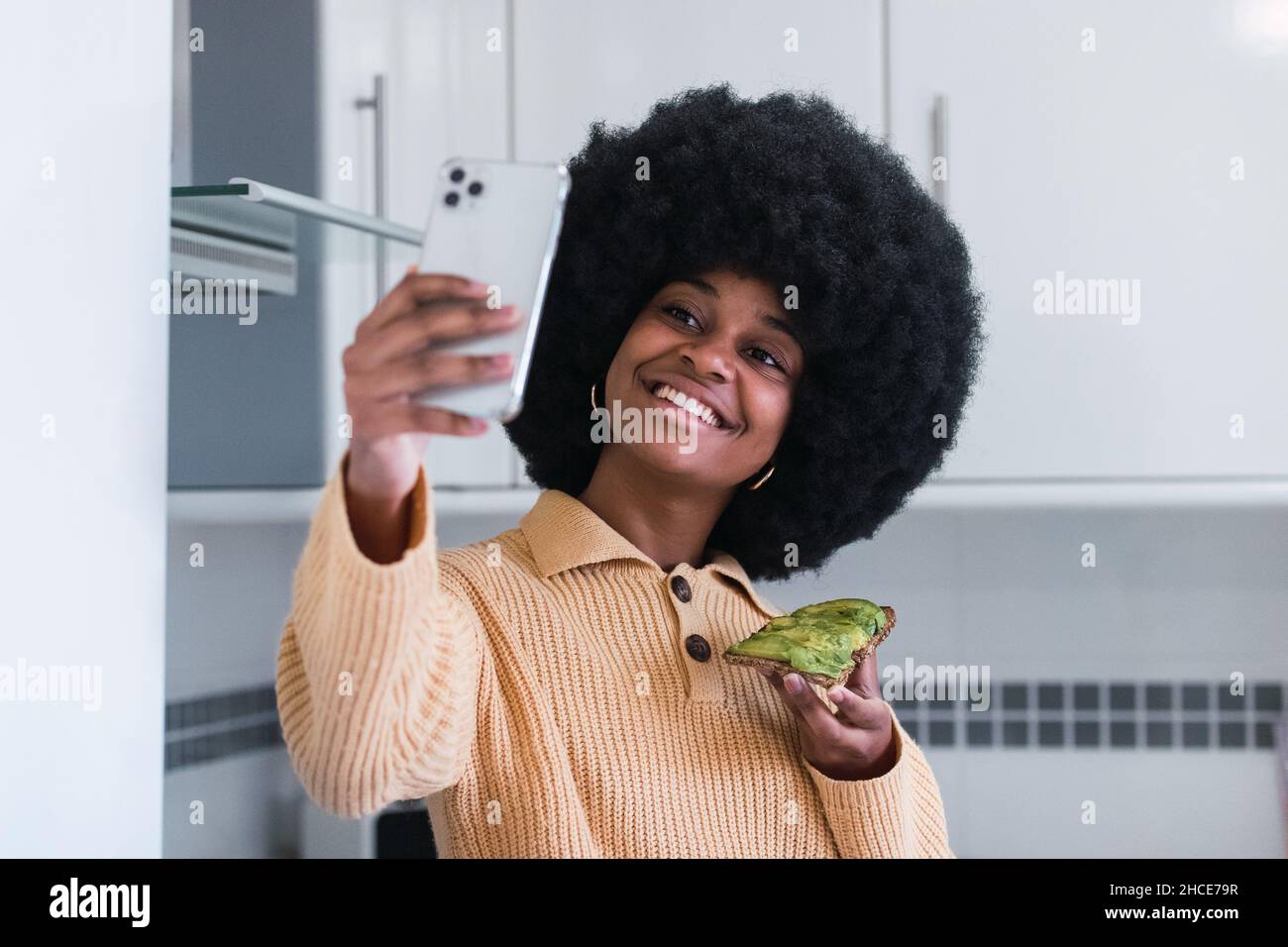 Positive African American female with Afro hairstyle wearing home ...