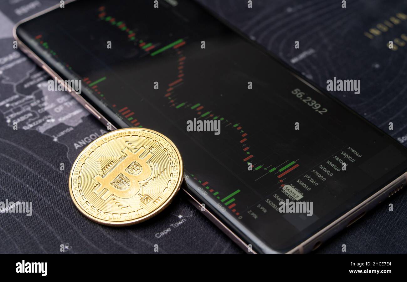 Stack of various bitcoins scattered on mobile phone display with ...