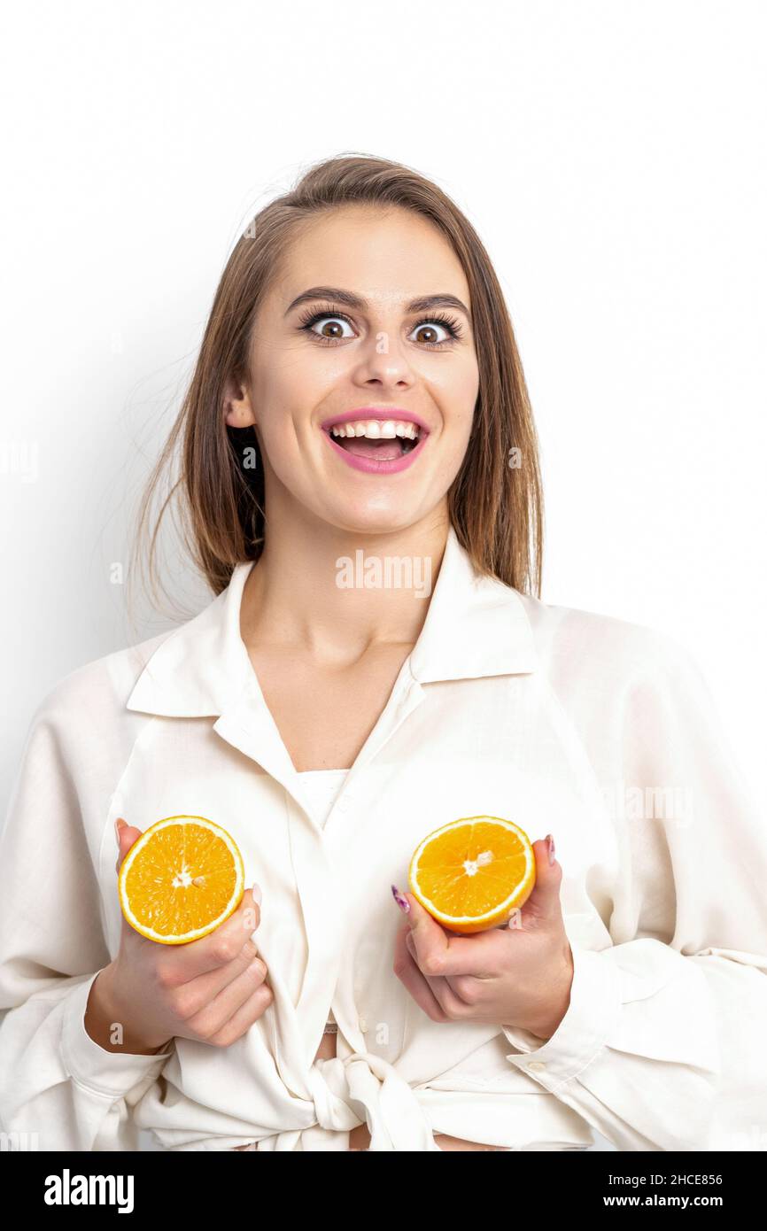 Joyful attractive young woman having two pieces of orange isolated on ...