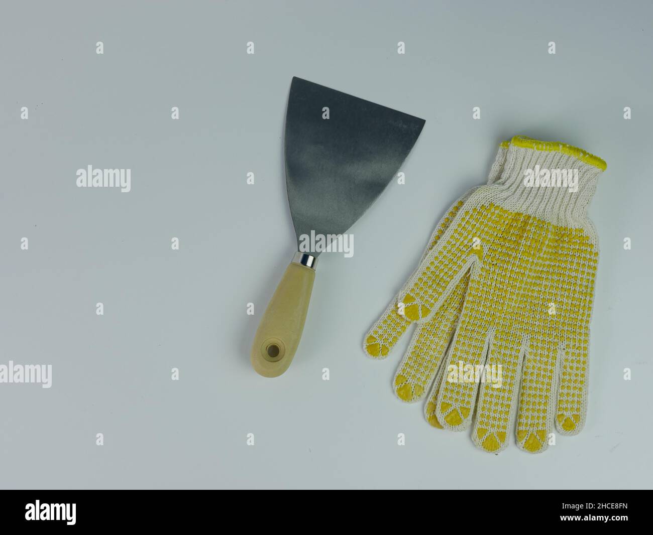 Scrapper or putty knife and work gloves isolated on white background ...