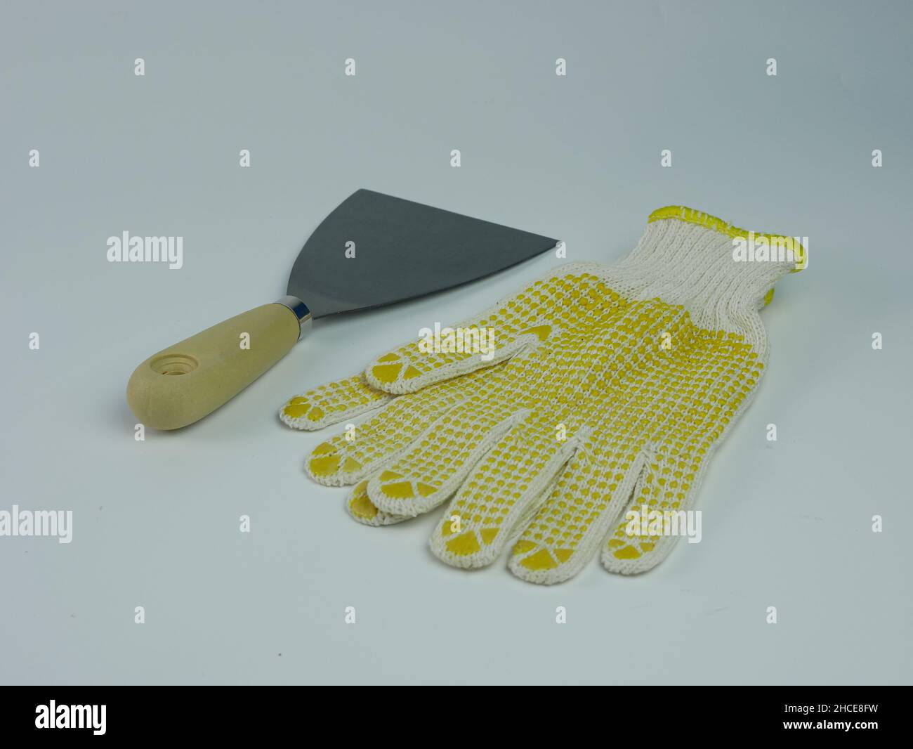 Scrapper or putty knife and work gloves isolated on white background ...